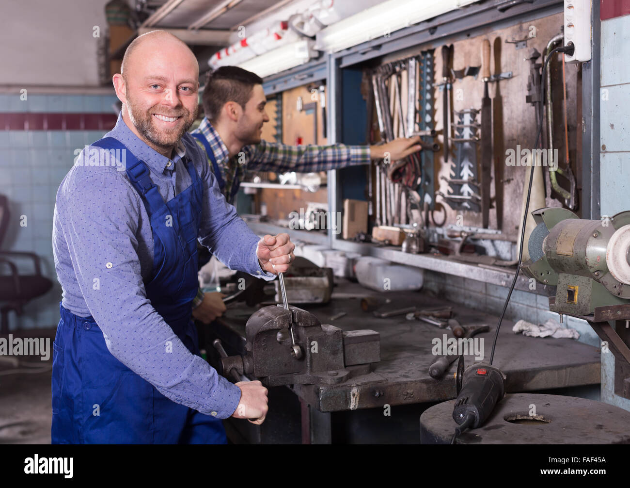 Two happy workmen toiling in locksmiths workshop and smiling Stock ...