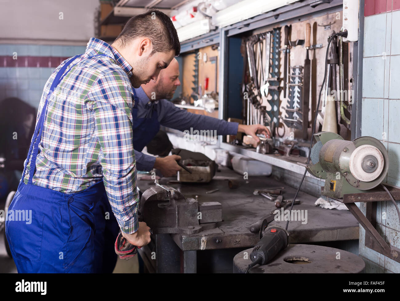 Two adult men are working in a workshop with various tools Stock Photo ...