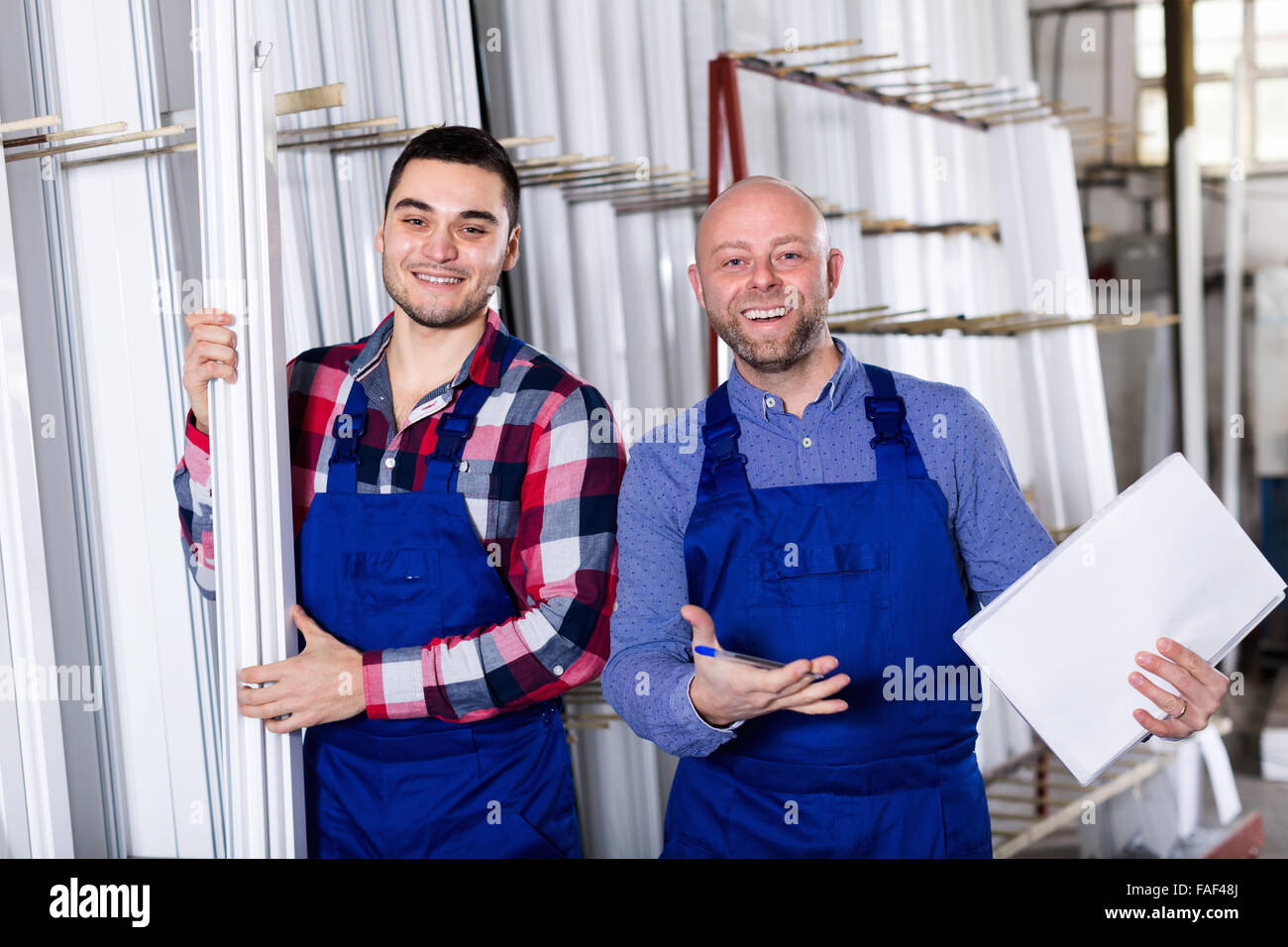Careful worker in uniform operating in lathe, his boss with papers ...