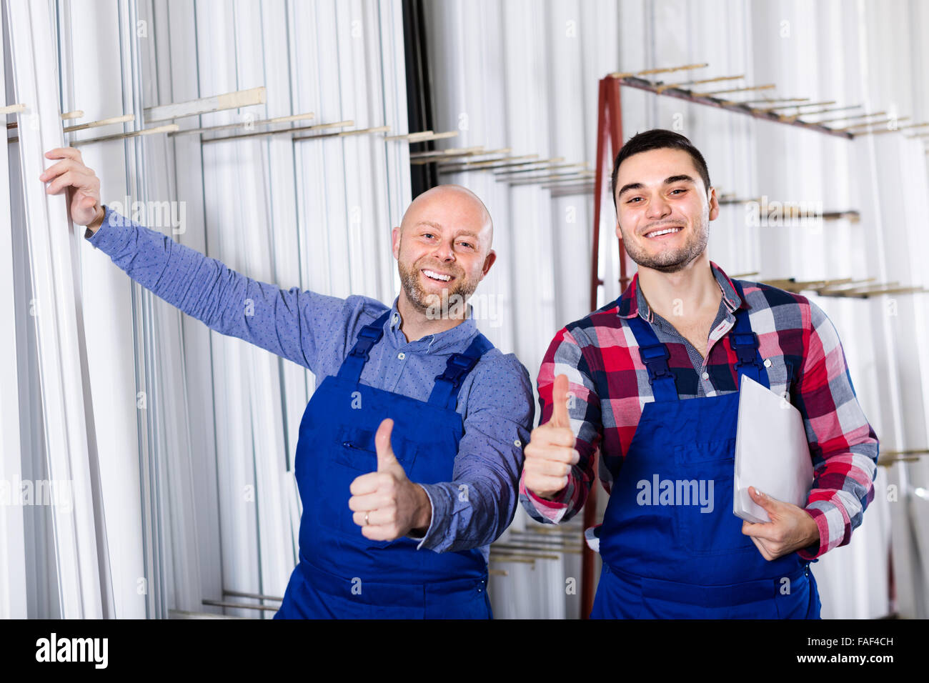 Two cheerful smiling workmen enjoying of production plan overfulfilment ...
