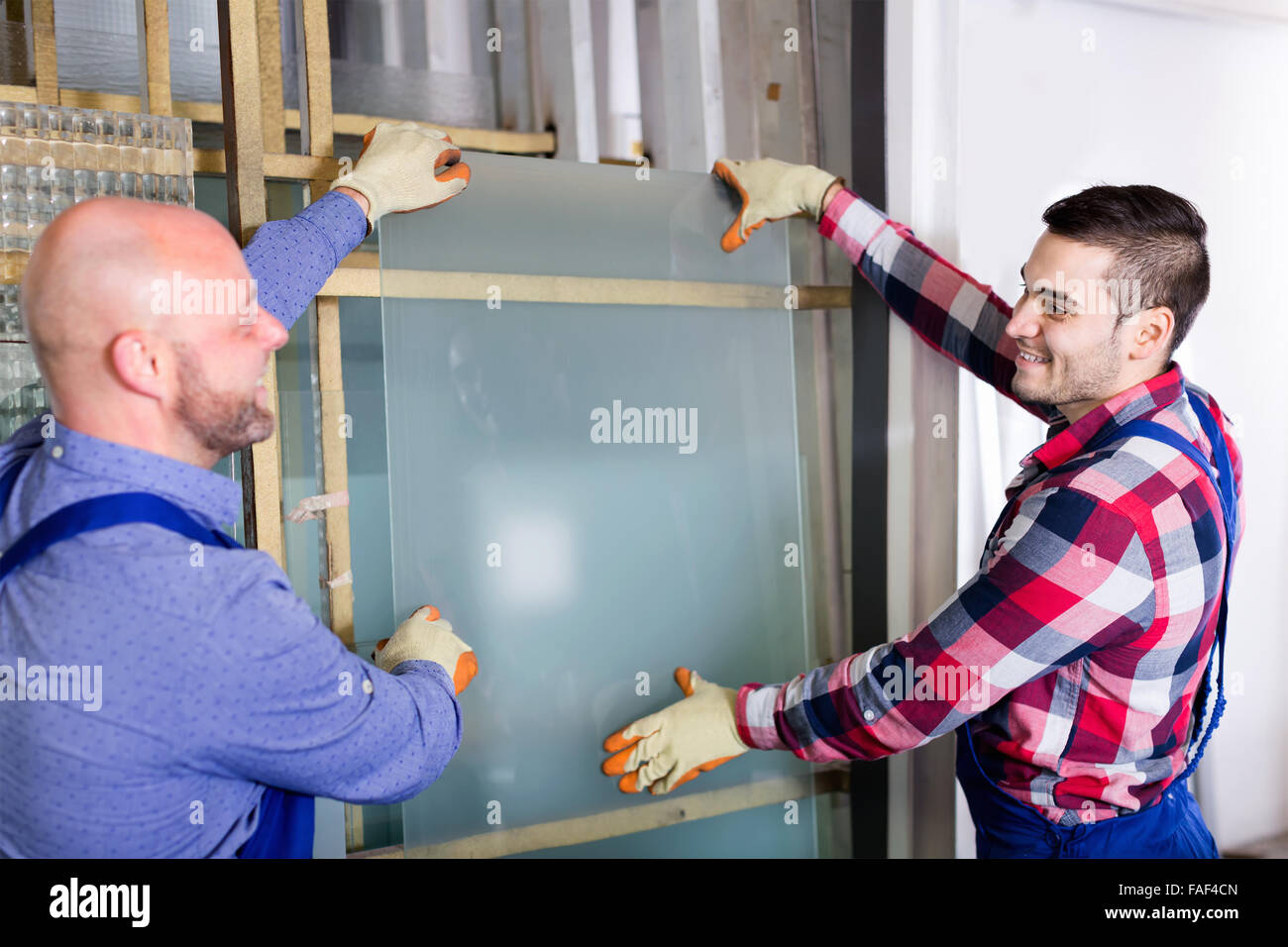 Two careful workers working with glass at modern factory Stock Photo ...