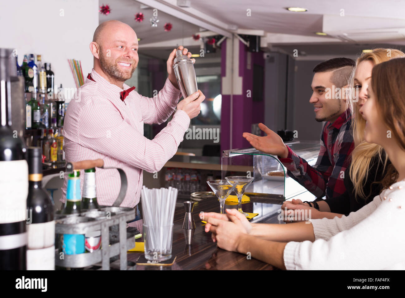Happy friends drinking and chatting with barman at bar counter Stock ...