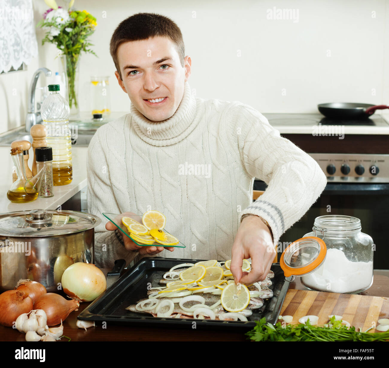 Handsome guy cooking trout fish with lemon in roasting pan Stock Photo ...