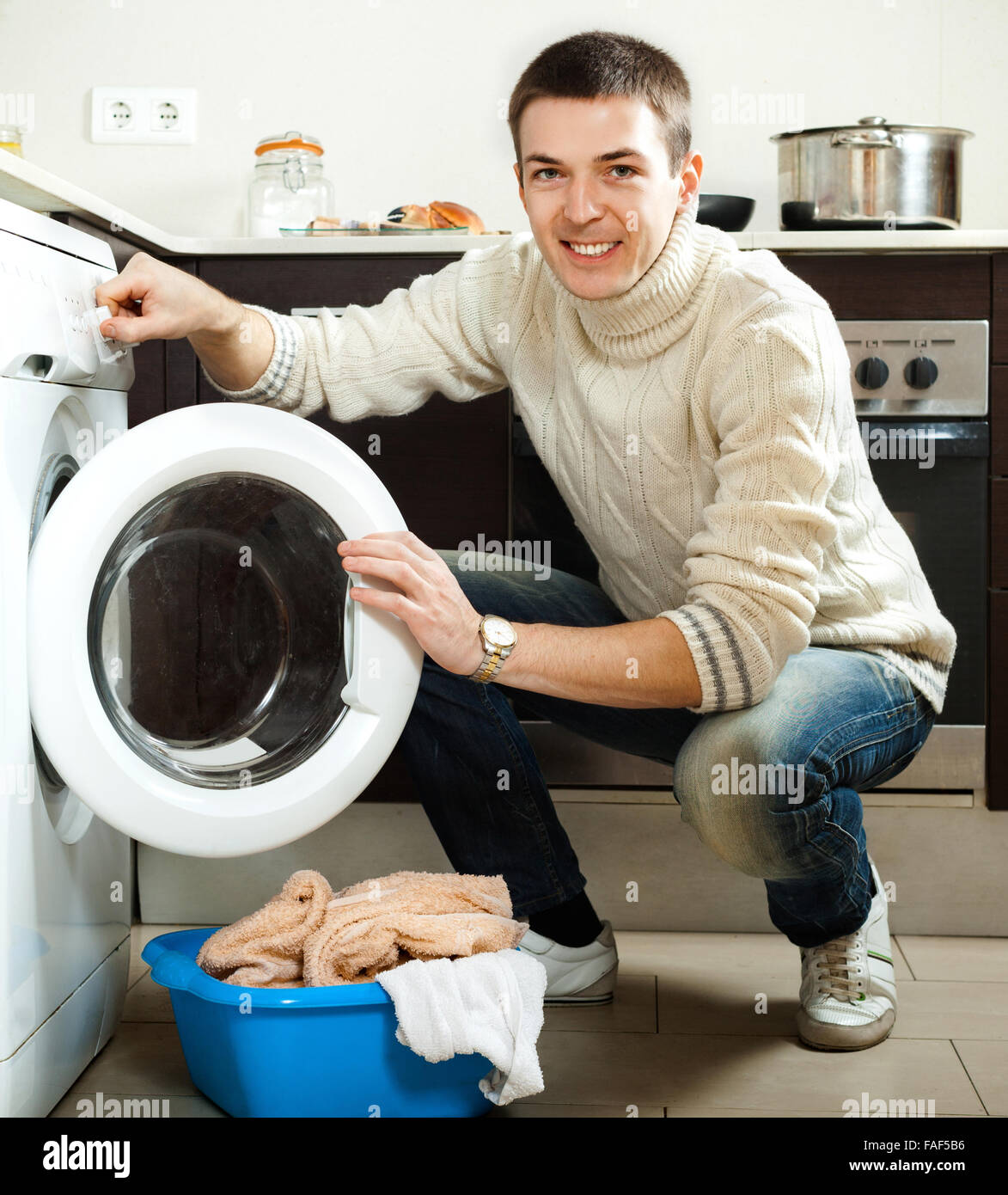 Handsome guy loading the washing machine in kitchen Stock Photo - Alamy