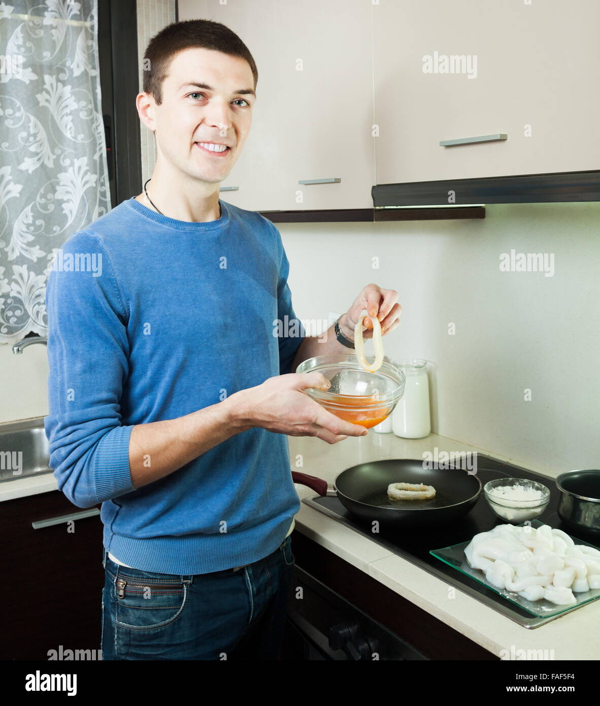 Smiling guy frying calamary in batter at kitchen Stock Photo - Alamy