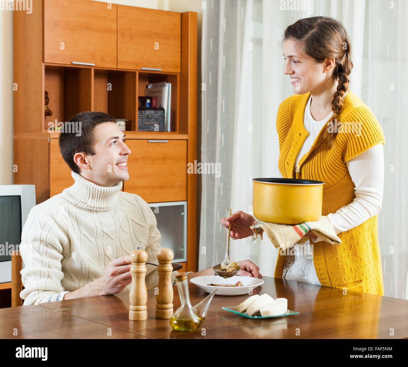 Ordinary girl serving lunch loving guy at table Stock Photo - Alamy