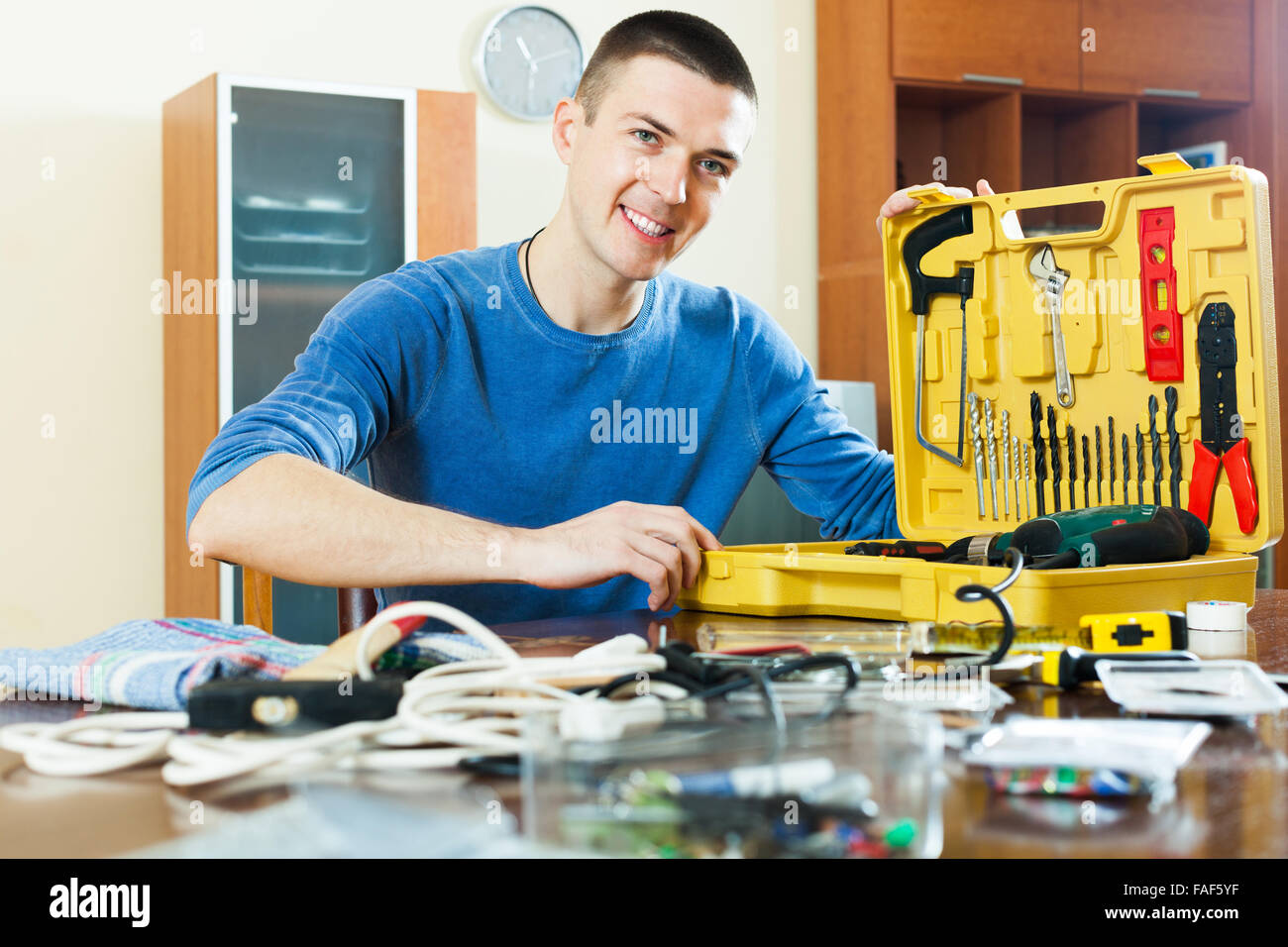 Happy handsome smiling guy sitting at table and showing toolbox Stock ...