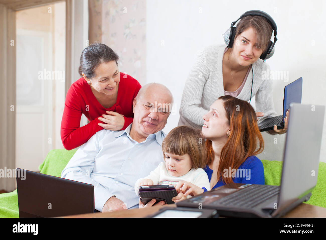 Happy family of three generations uses few various electronic devices ...
