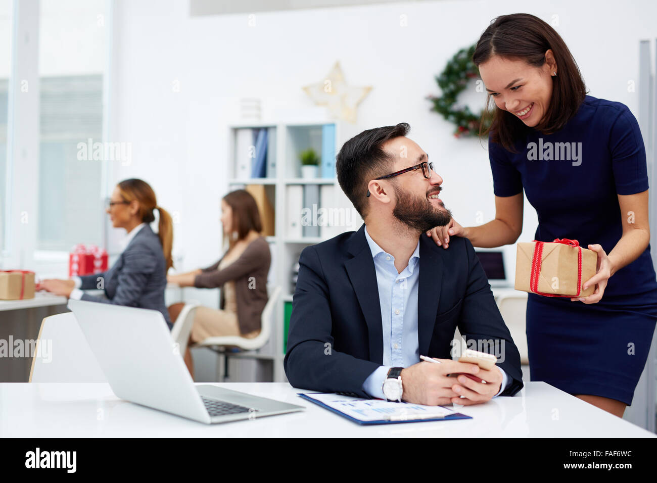 Young businesswoman giving her colleague Christmas present at office ...