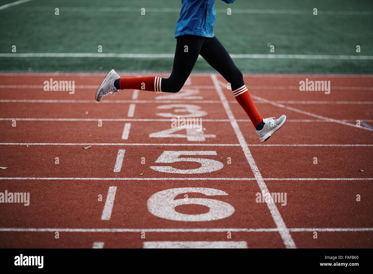 Woman running on athletic track on stadium Stock Photo - Alamy
