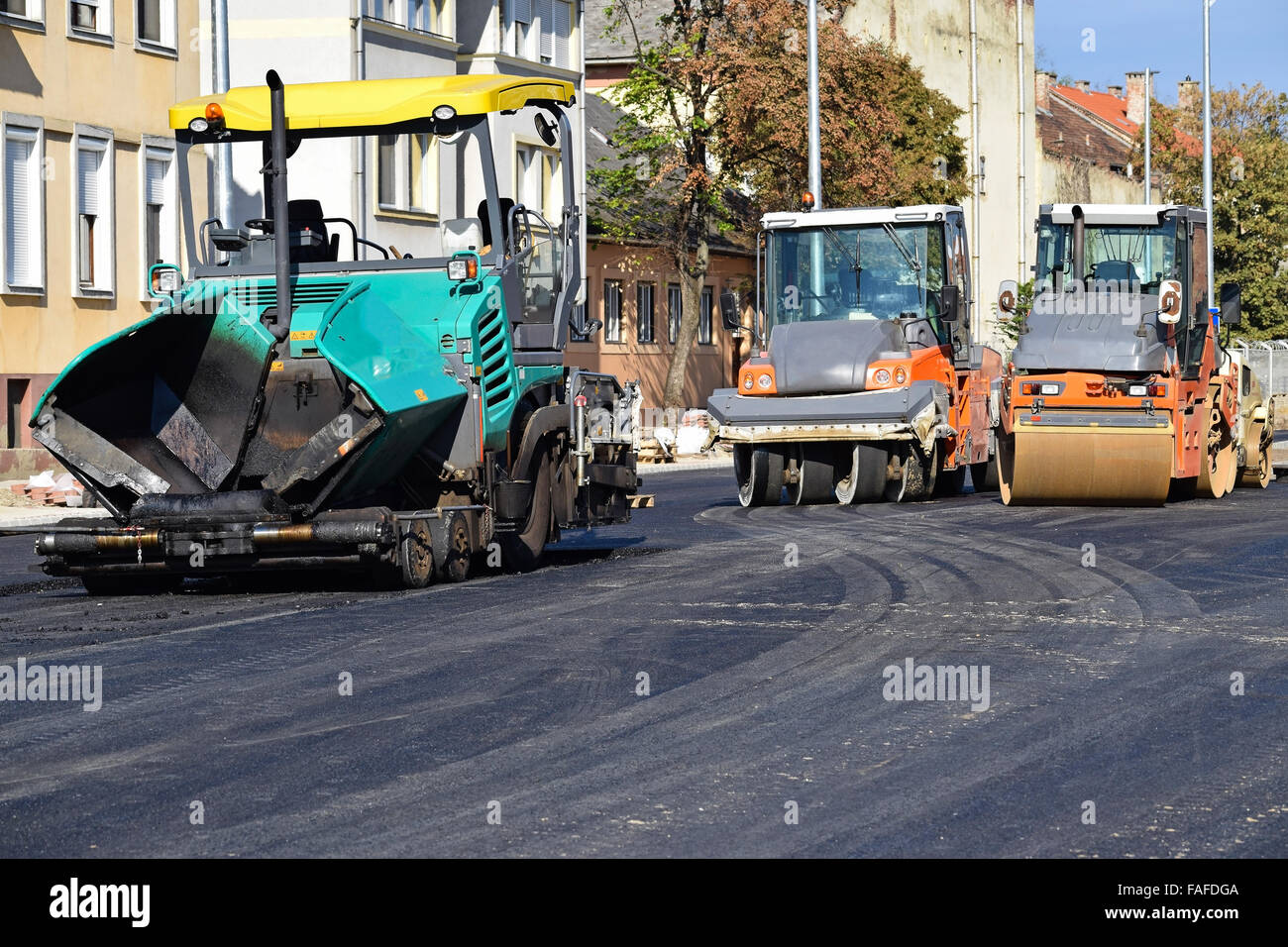 Asphalt paving vehicle and road roller at the road construction Stock ...