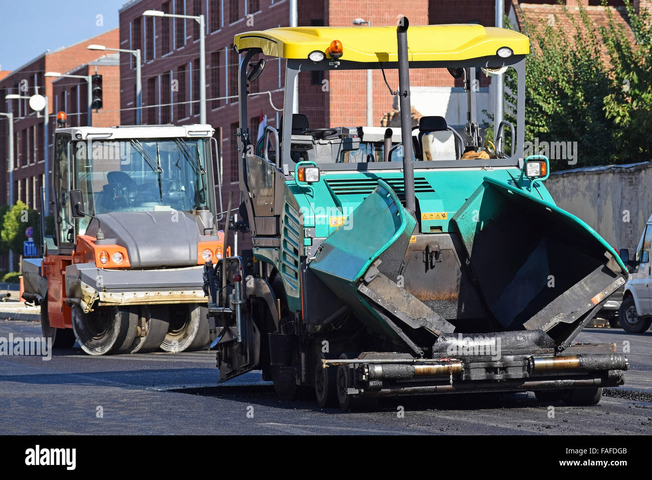 Asphalt paving vehicle and road roller at the road construction Stock ...