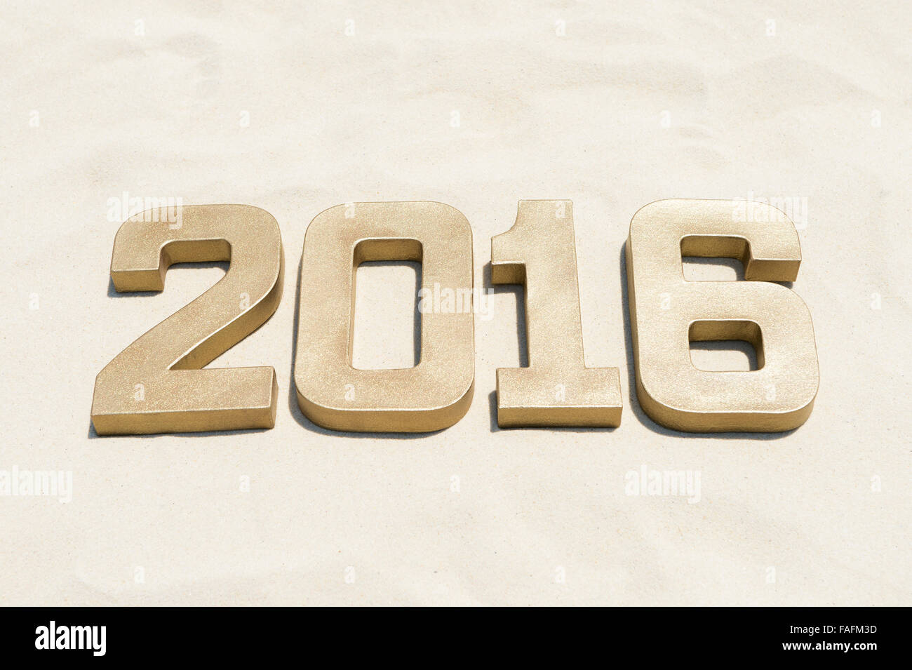 Golden 2016 sign in block numbers sitting on sand beach background in ...