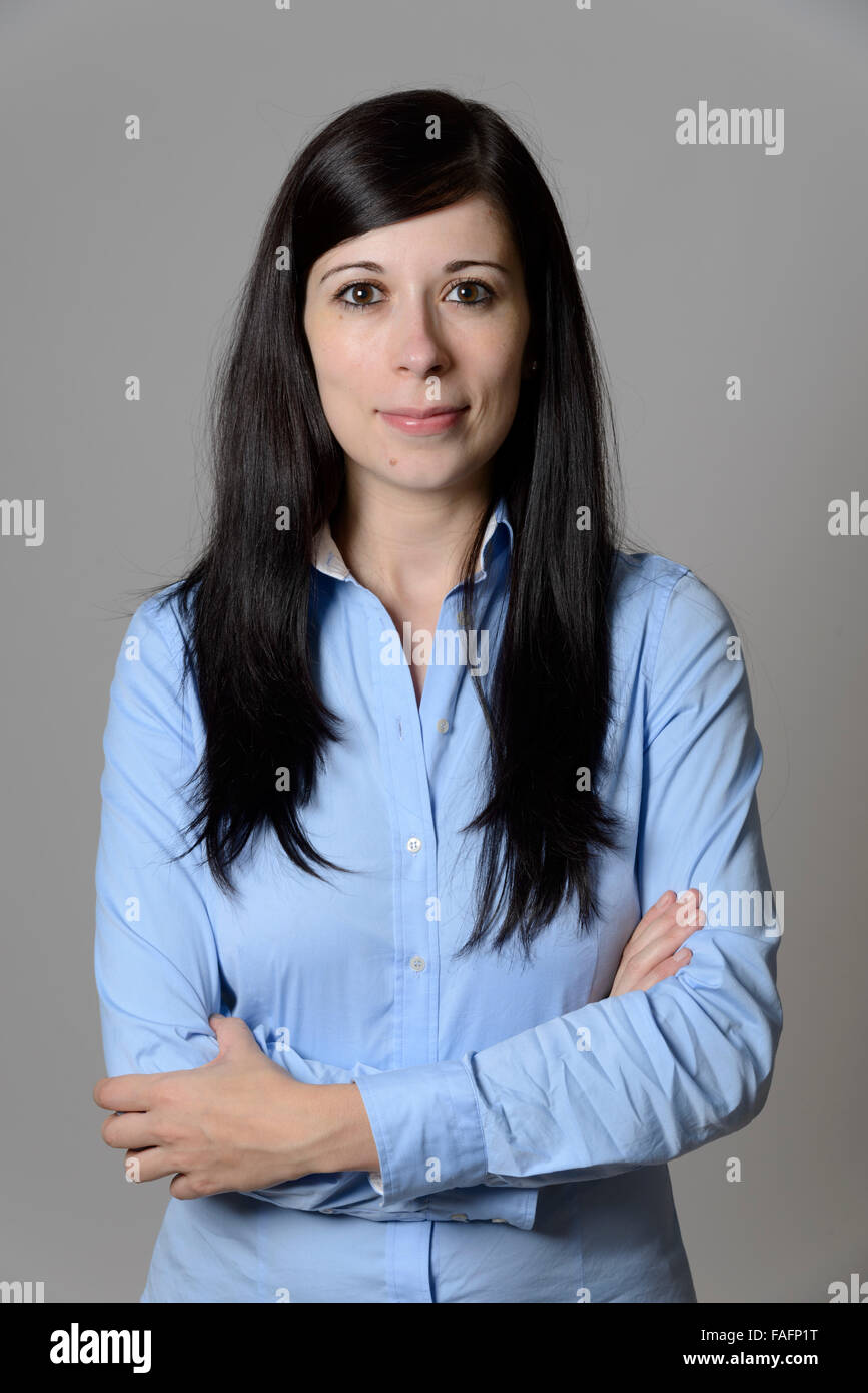 Portrait of business woman with long dark hair and her arms folded ...