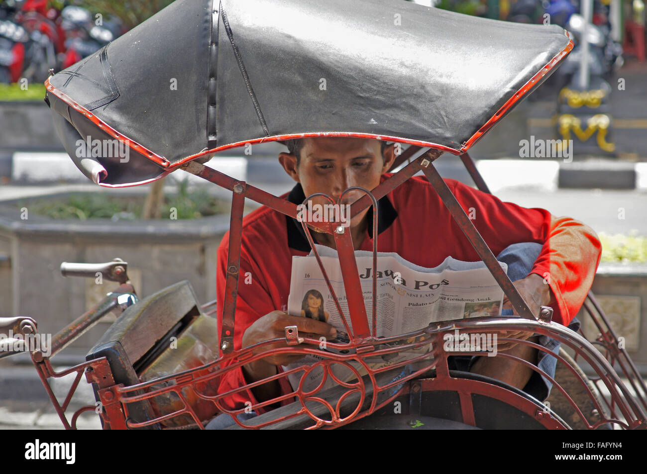 Javanese rickshaw driver reading newspaper Stock Photo - Alamy