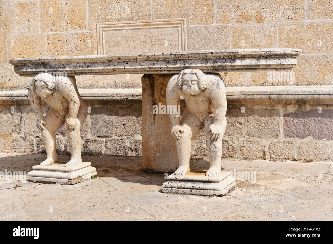 A medieval stone table is supported by two statues of the hunched men ...
