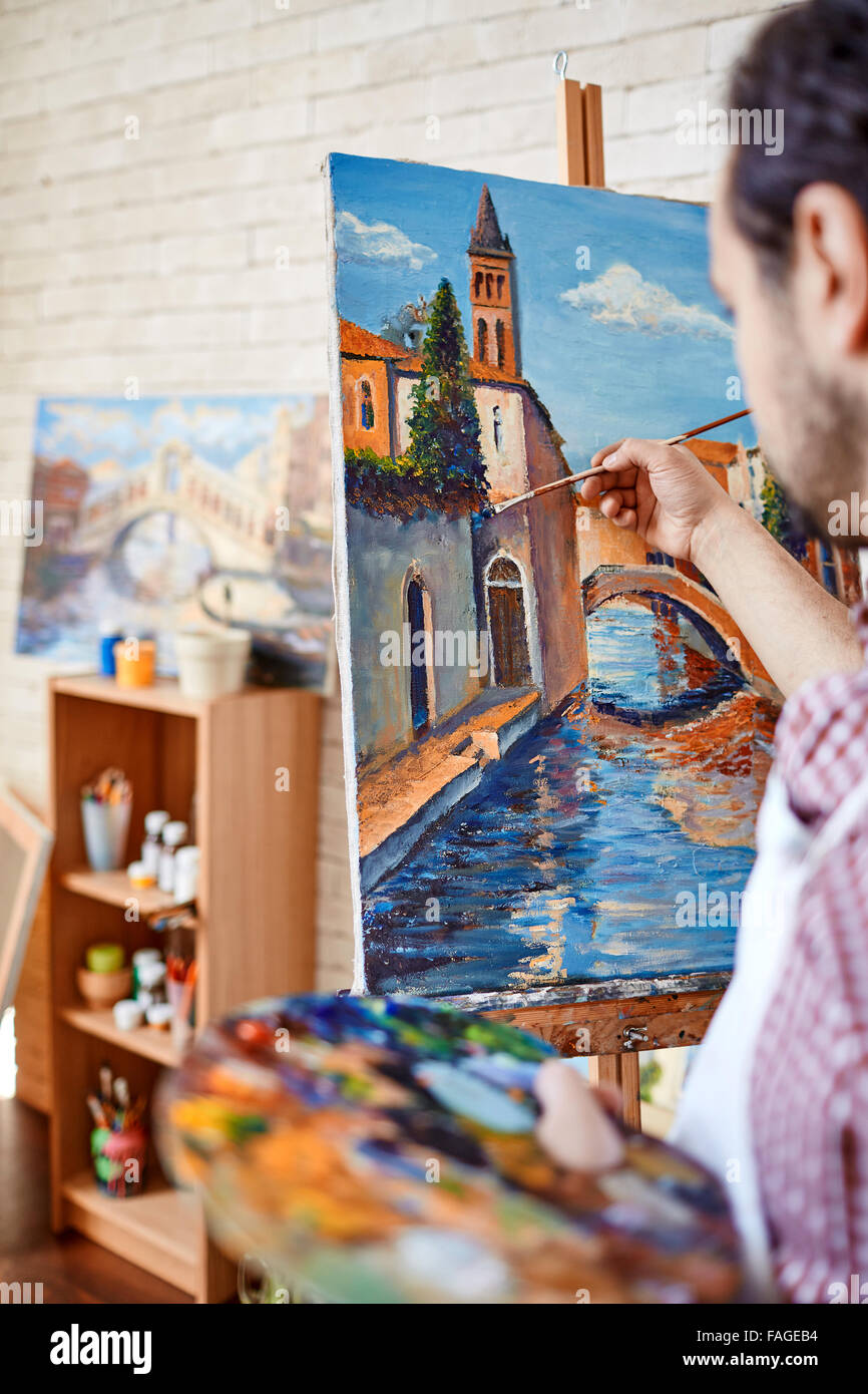 Young artist with palette painting on canvas Stock Photo - Alamy