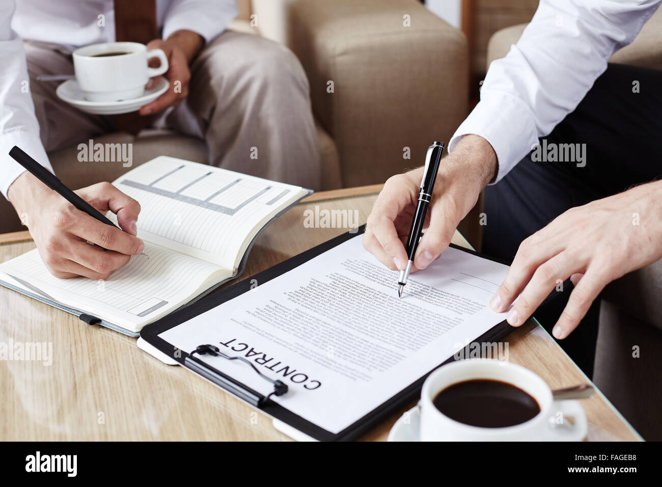 Male employee reading contract while his colleague making notes Stock ...