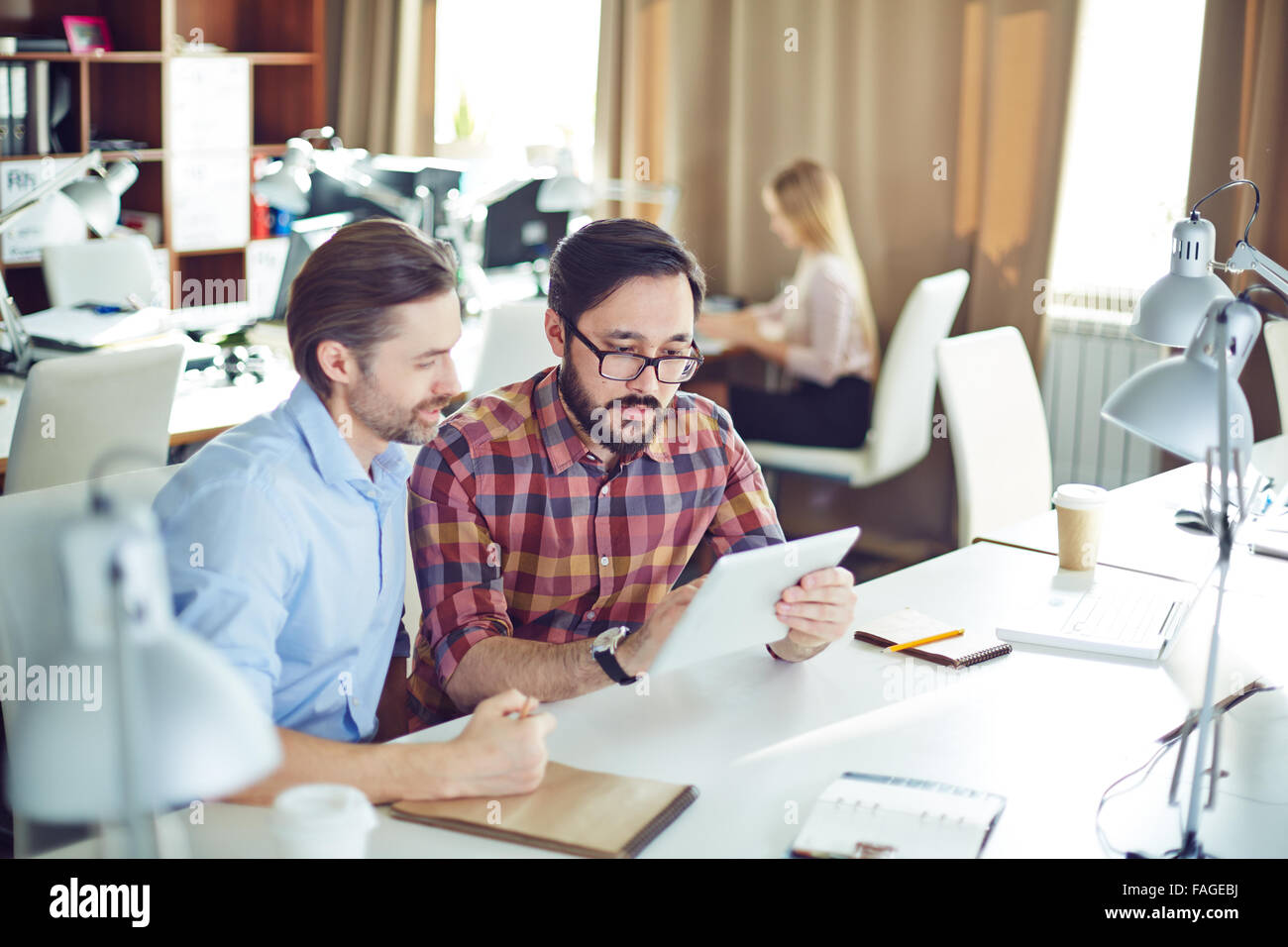 Two serious businessmen using touchpad while analyzing data Stock Photo ...