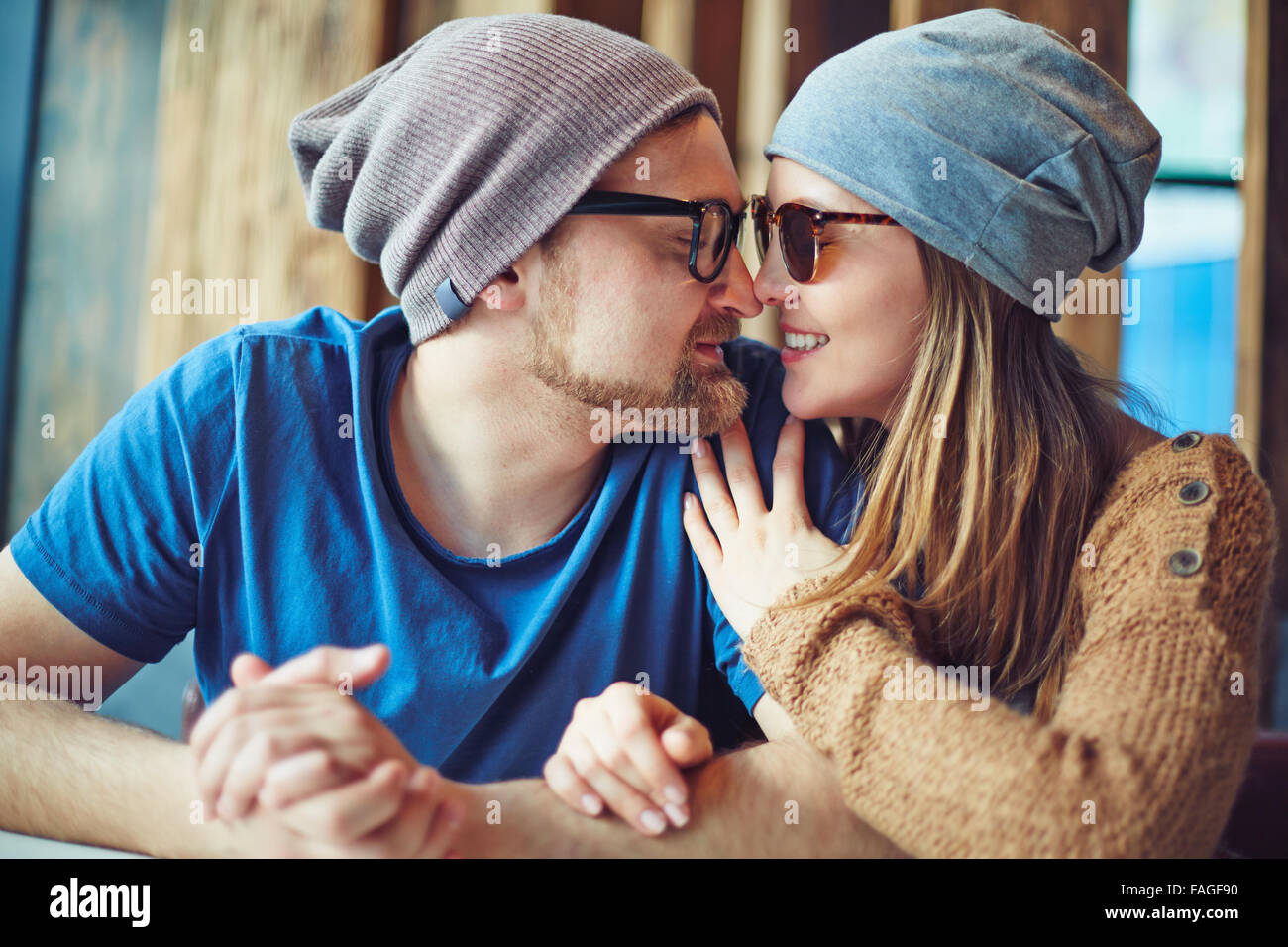 Amorous couple in caps and eyewear sitting face to face Stock Photo - Alamy