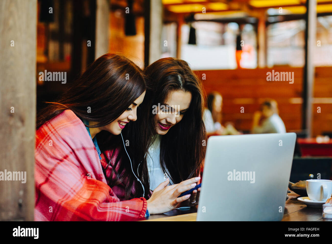 Two girl sitting listening music Stock Photo - Alamy