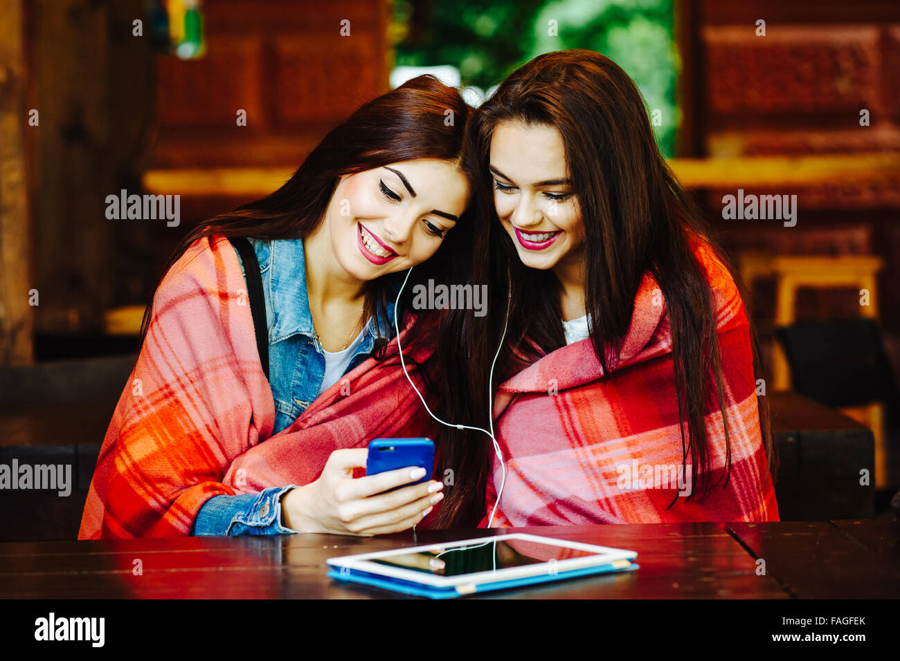 Two girl sitting listening music Stock Photo - Alamy