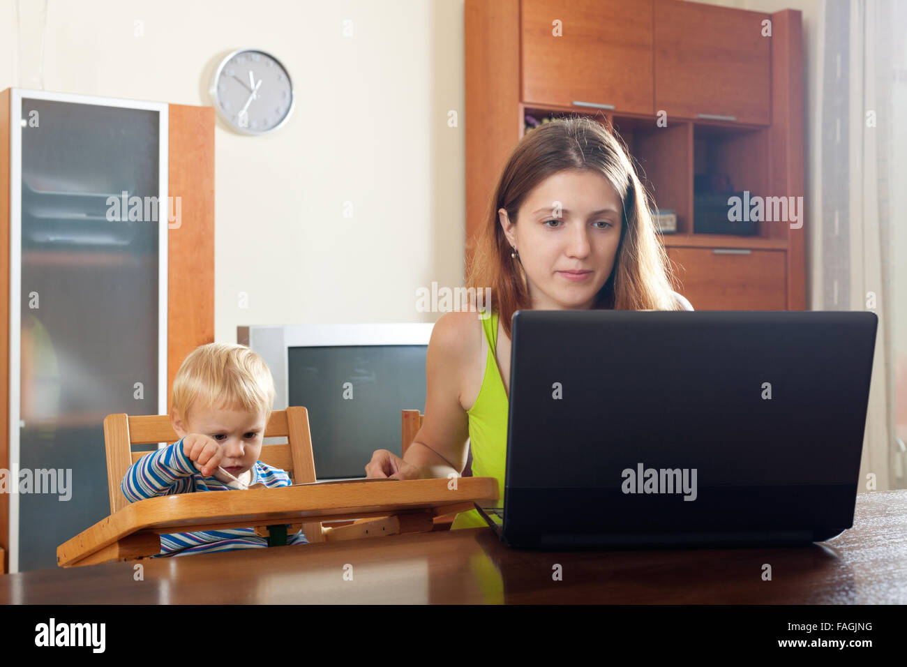 Whiner woman with a crying baby, working on the Internet with a laptop ...