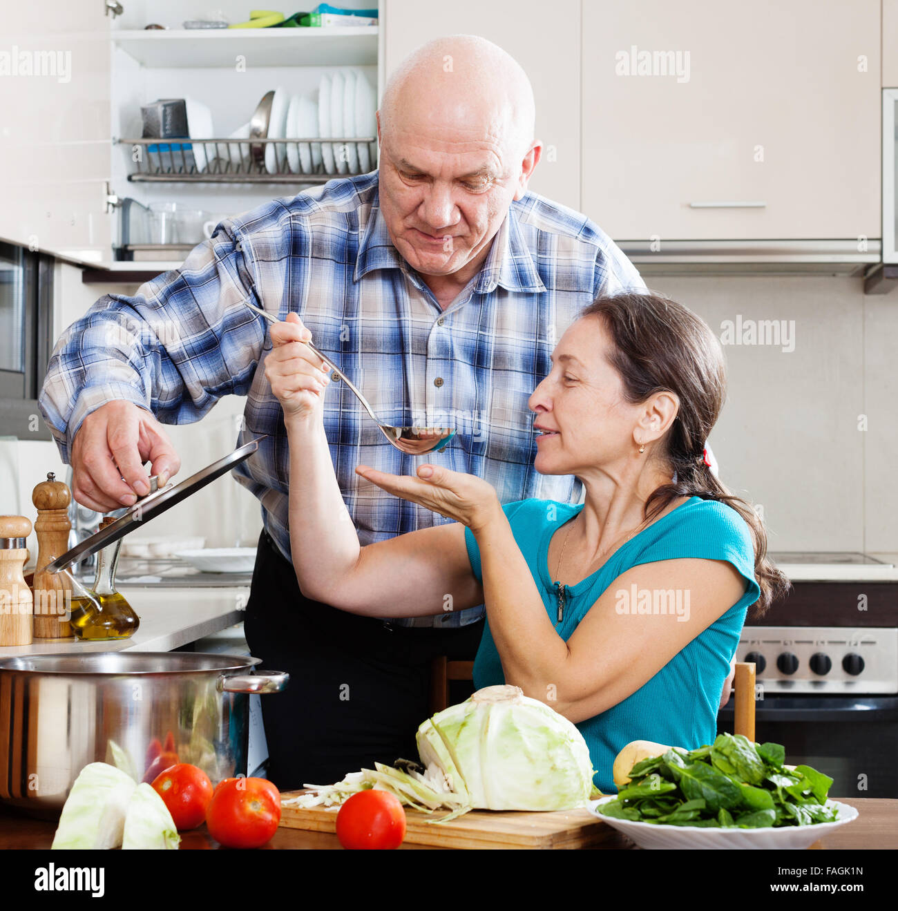 happy ordinary mature couple cooking lunch with vegetables in home ...