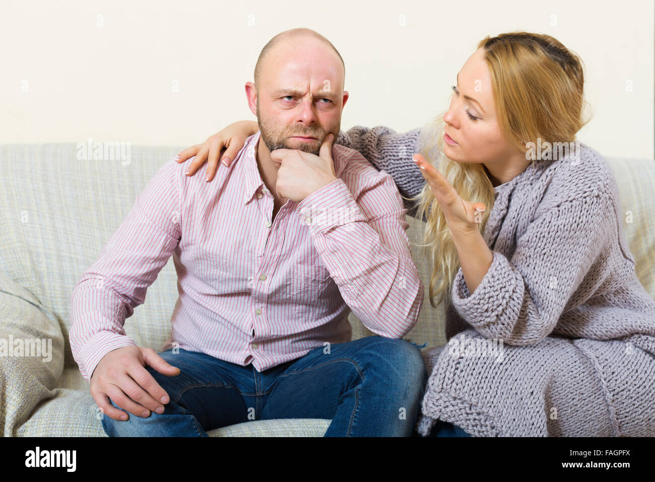 Sad man has problem, loving woman consoling him on sofa at home. Focus ...