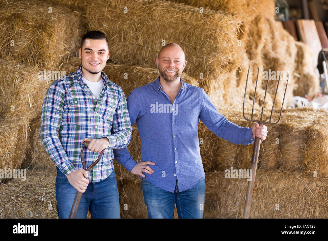 Portrait of two farmers with working tools in barn Stock Photo - Alamy