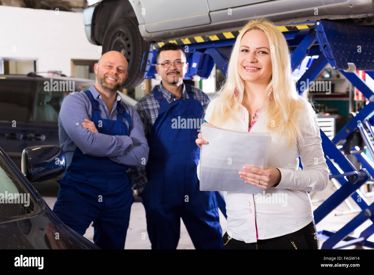 Attractive female insurance agent discussing with auto mechanics ...