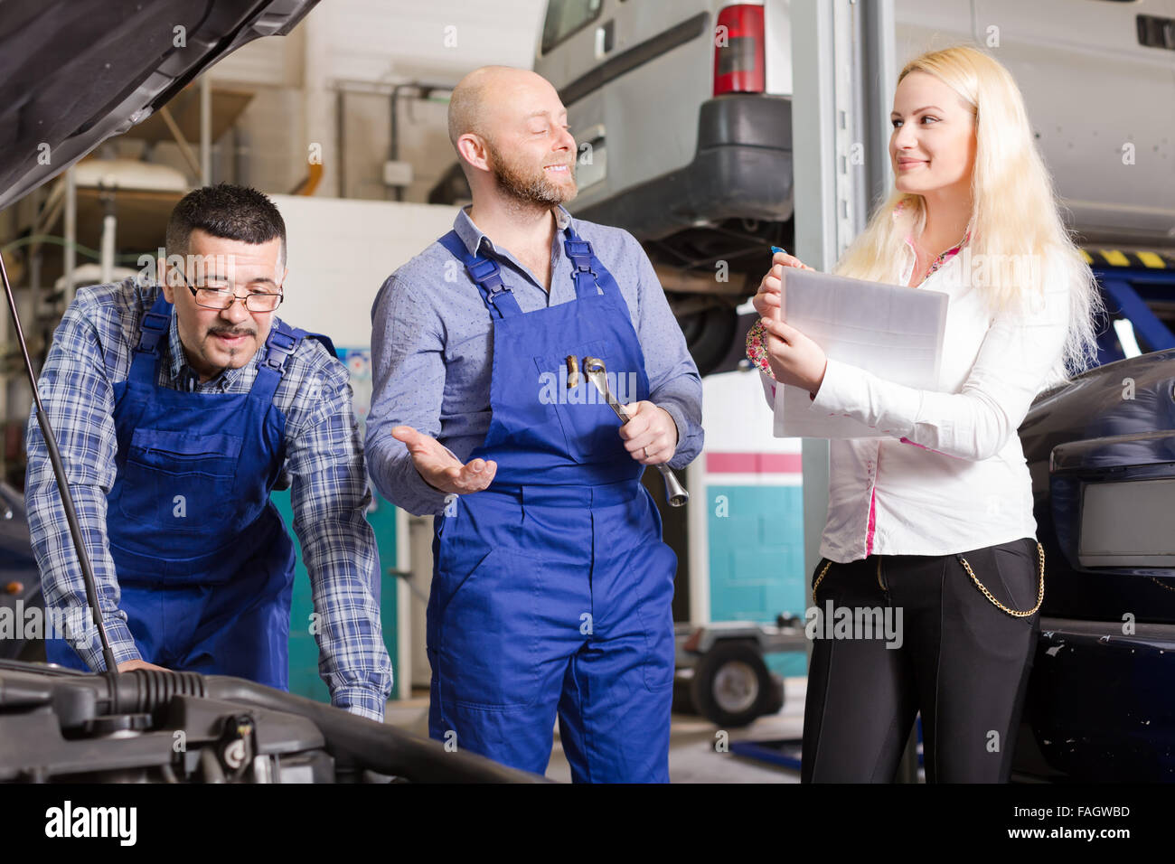 Female insurance agent discussing with smiling auto mechanics renewal ...