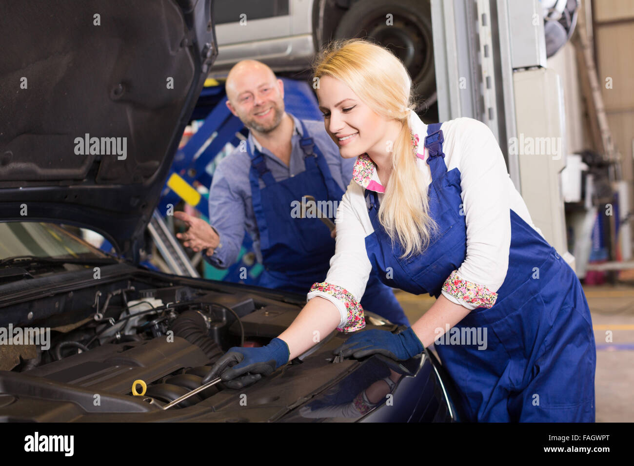 Handsome mechanic and female assistant working at auto repair shop ...