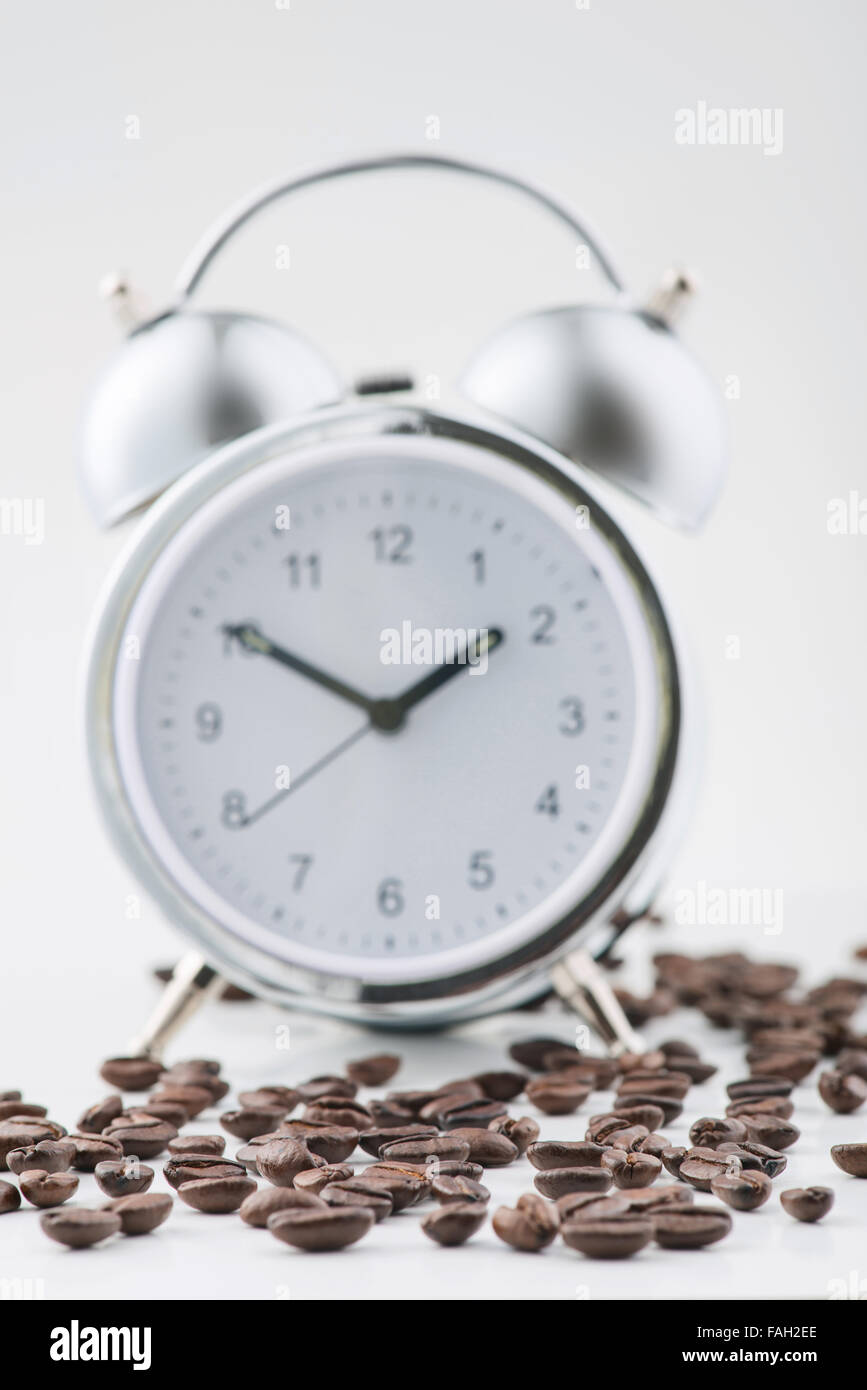 Alarm clock and coffee beans on white surface Stock Photo - Alamy