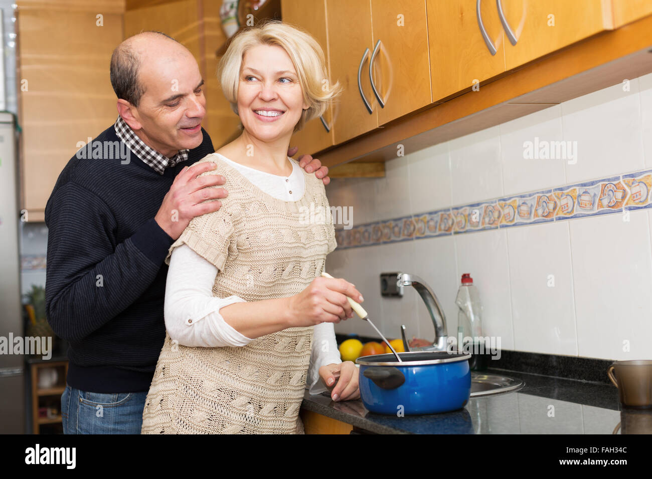 Mature husband helping happy wife to cook in kitchen Stock Photo - Alamy