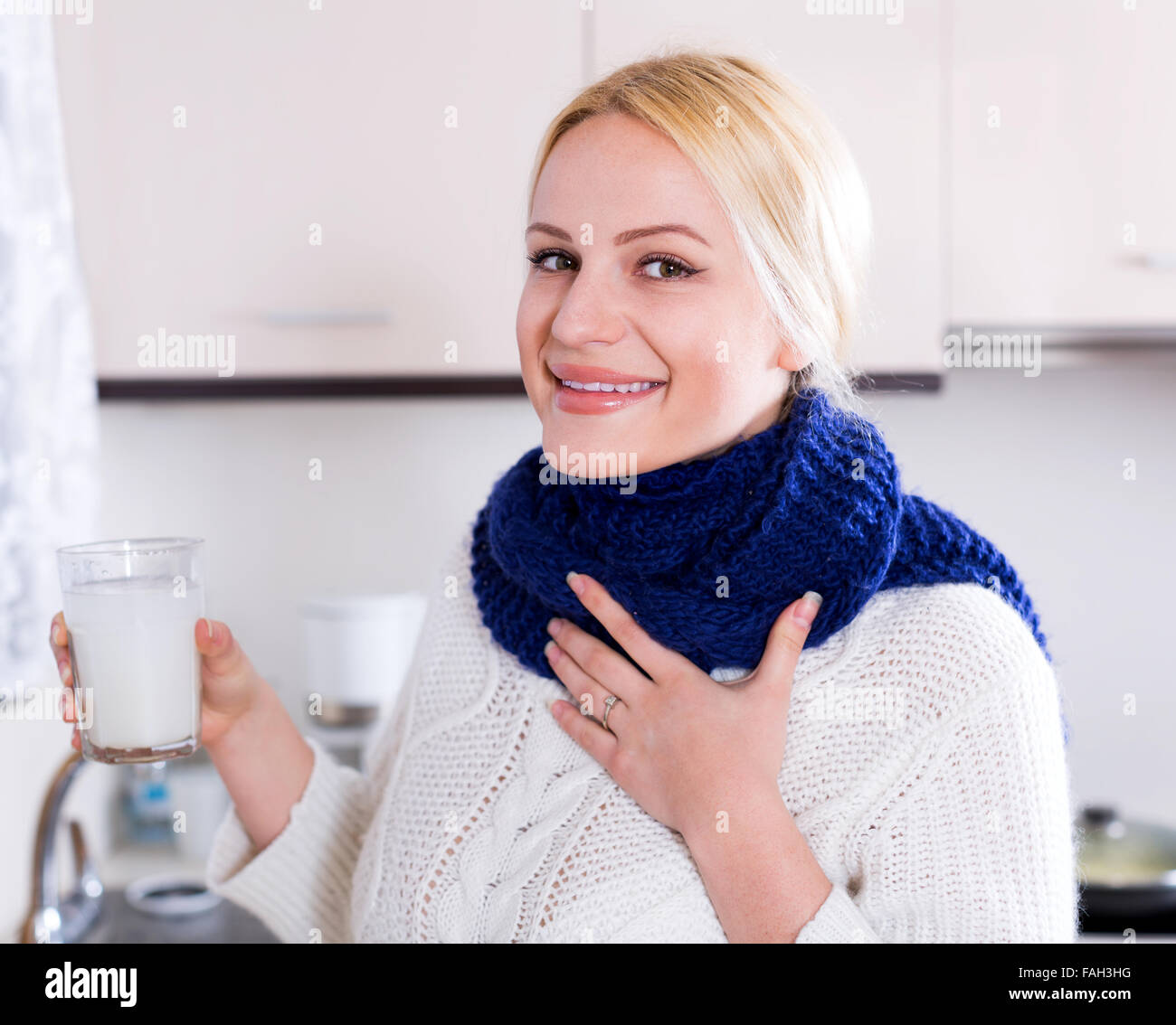 Happy blonde with scarf gargling at kitchen Stock Photo - Alamy