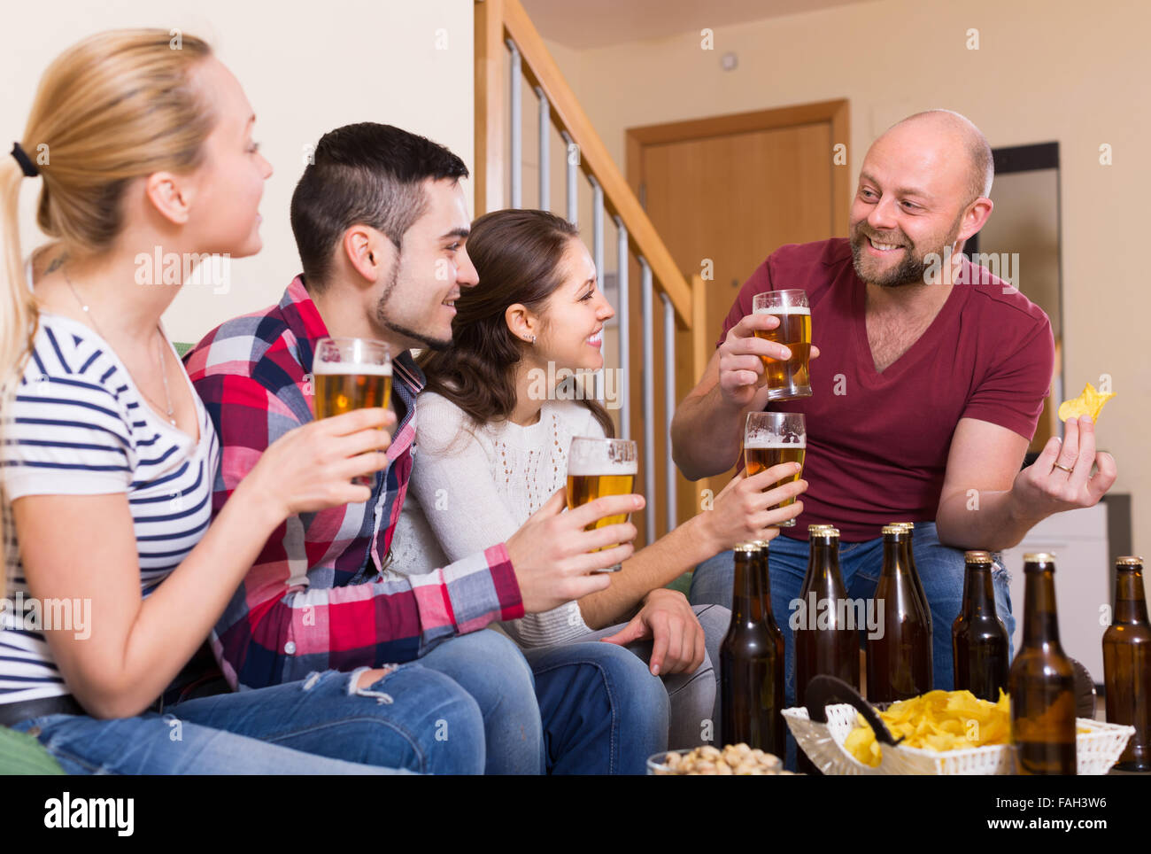 Cheerful happy young adults drinking beer and laughing indoor ...