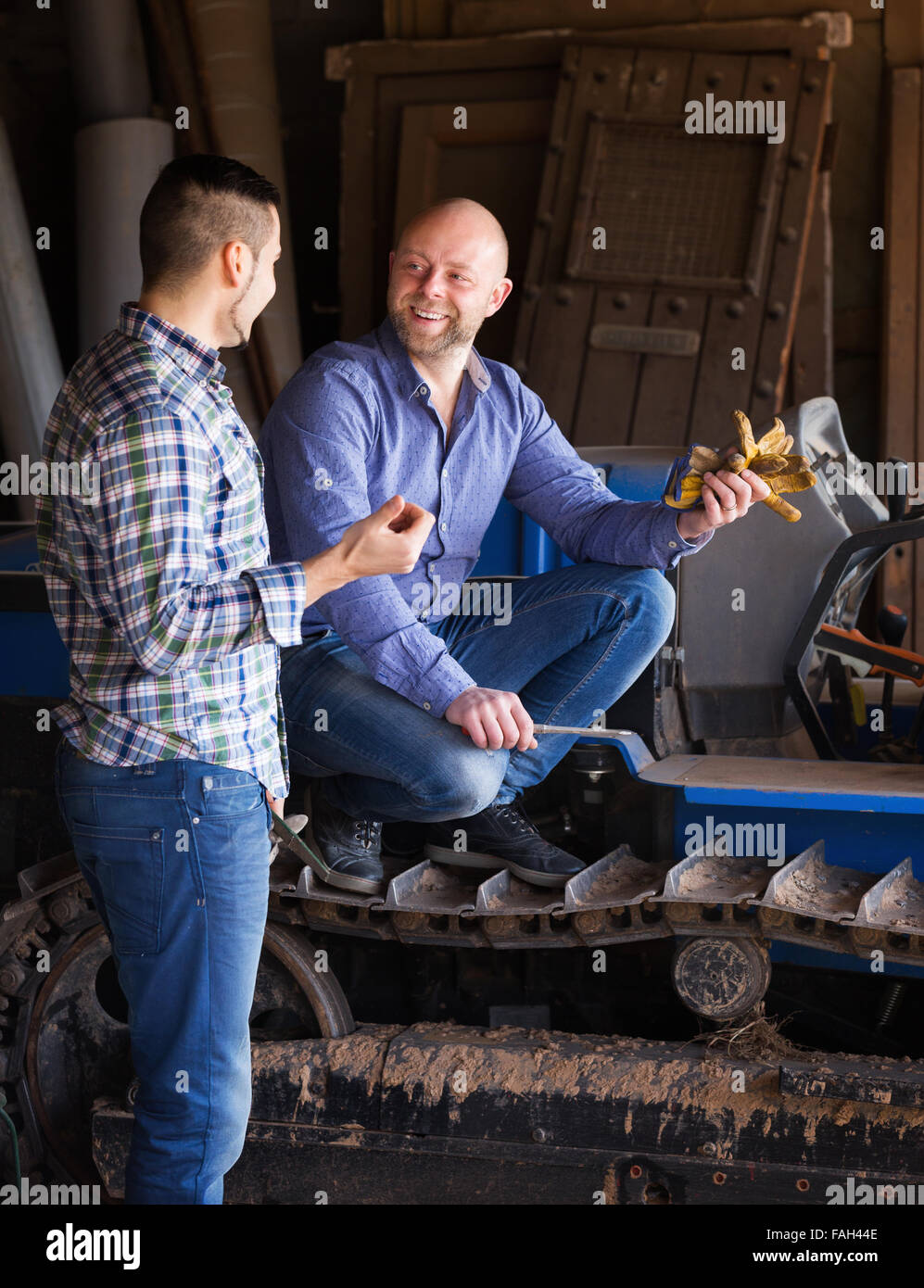 Two adult smiling male drivers working with tractor and chatting Stock ...
