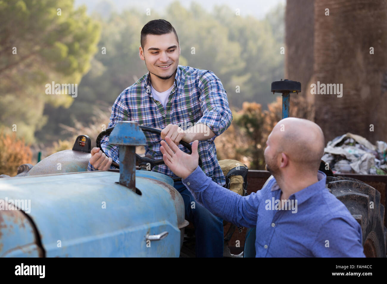 Two smiling russian mechanics reparing old agrimotors at farm Stock ...