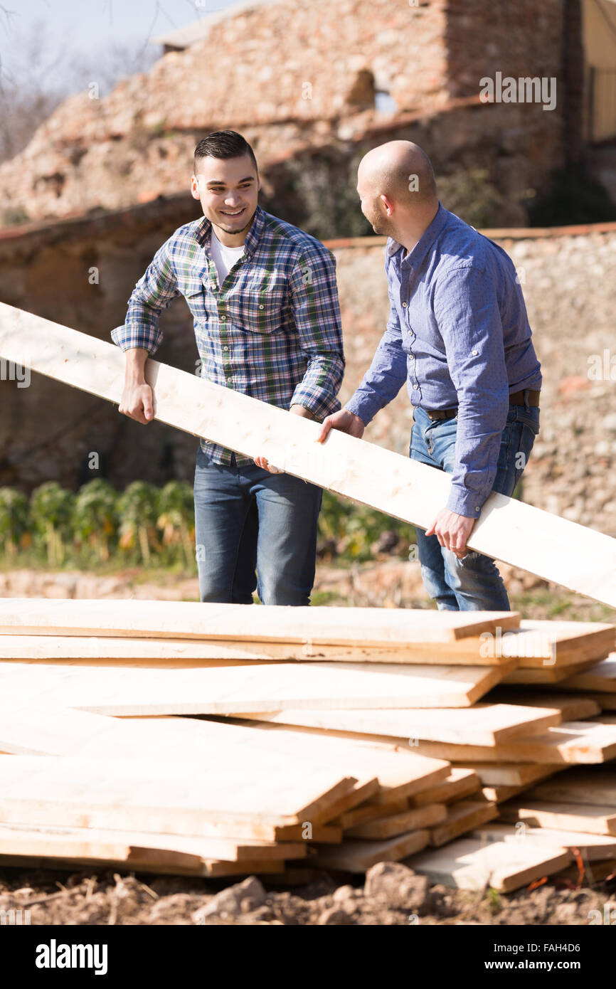 Smiling workmen arranging building timber at farm Stock Photo - Alamy