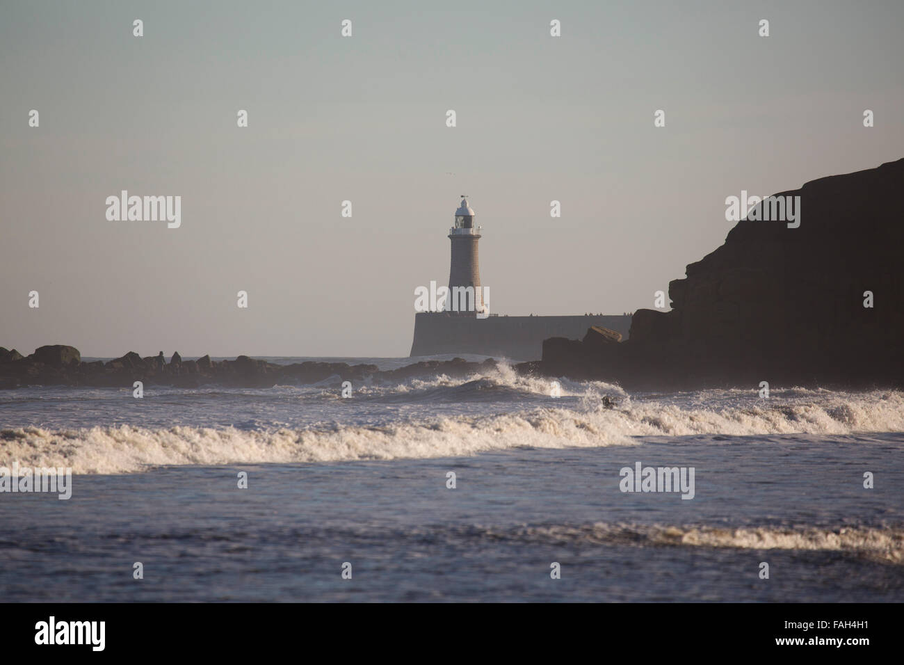 The pier and lighthouse at Tynemouth in England. North Sea waves break ...