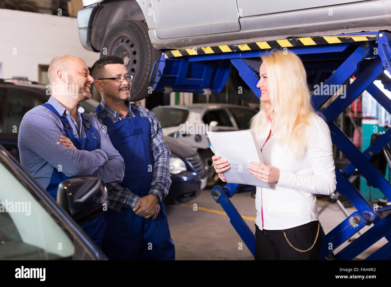 Smiling insurance agent discussing with mechanics renewal of car. Focus ...