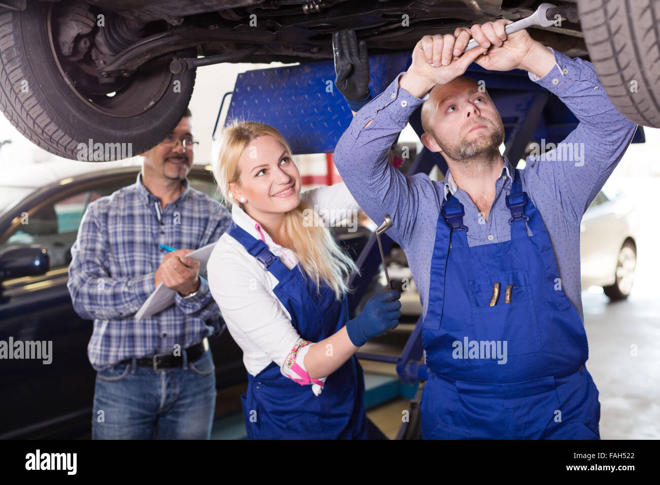 Handsome mechanic and female russian assistant working at auto repair ...