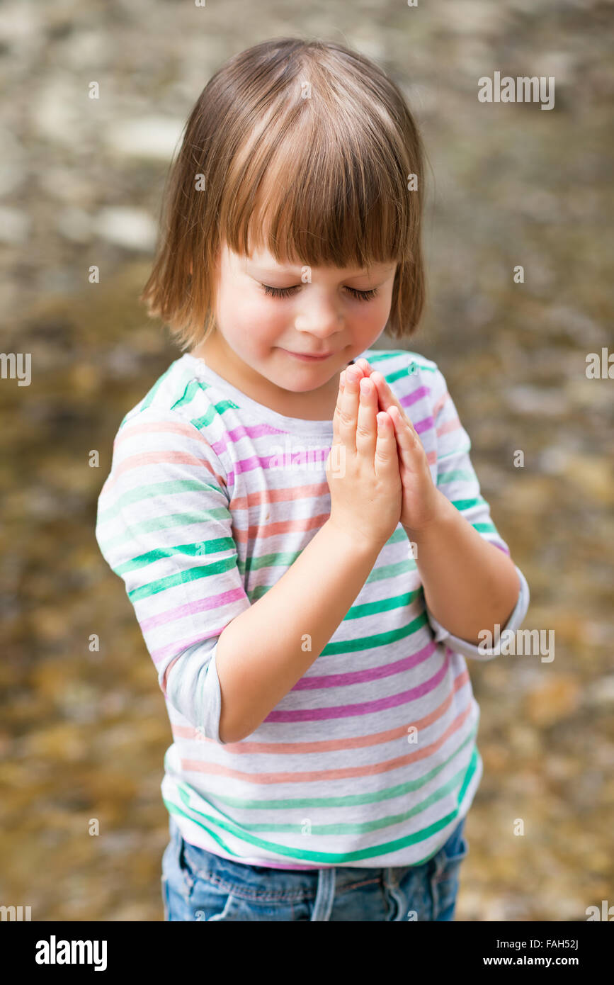 Cute little girl praying over textured background Stock Photo - Alamy