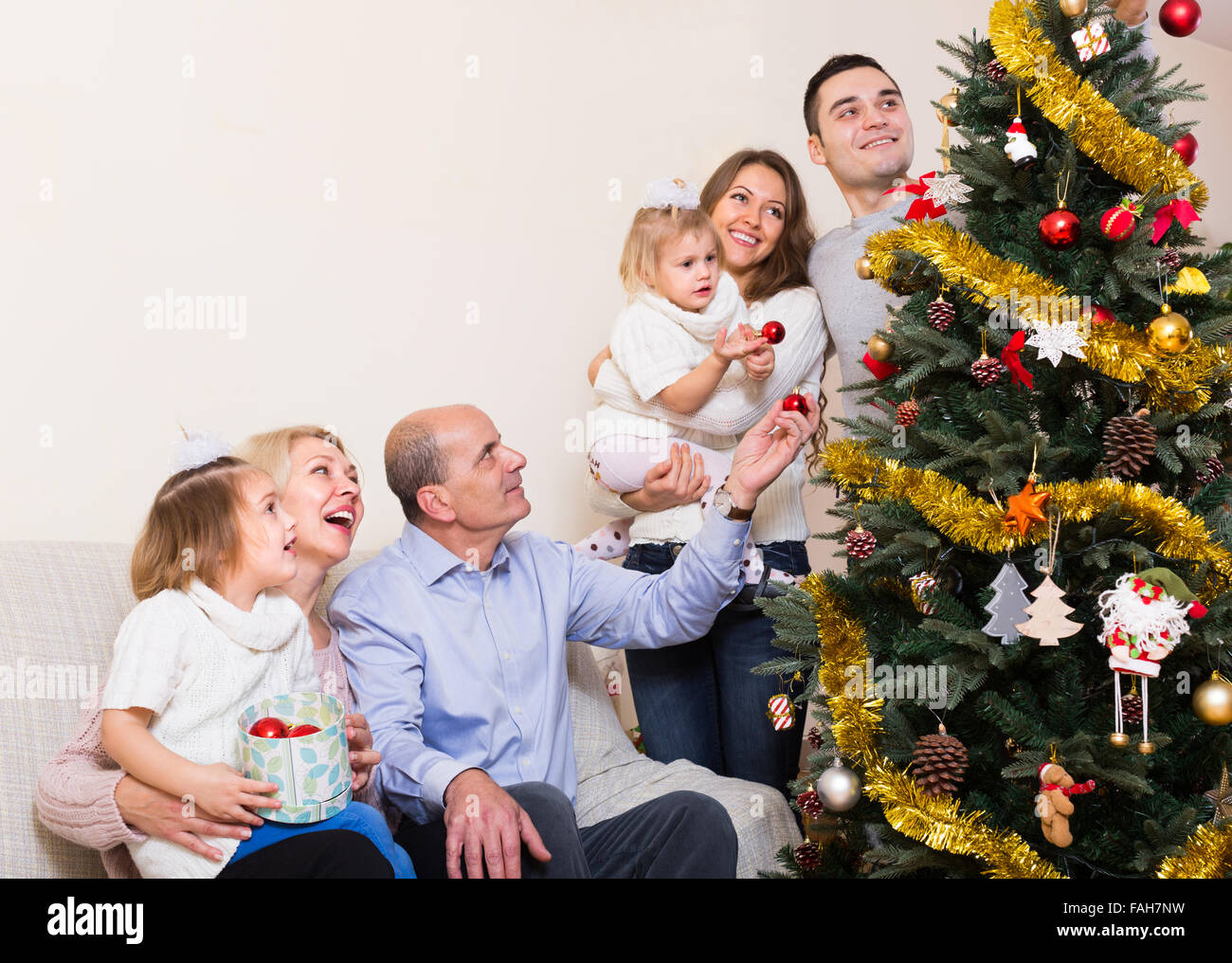Long family with grand children decorating christmas fir tree Stock ...