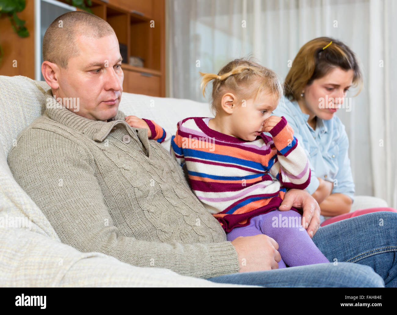 Problems in a family. Sad man is holding his crying daughter and his ...