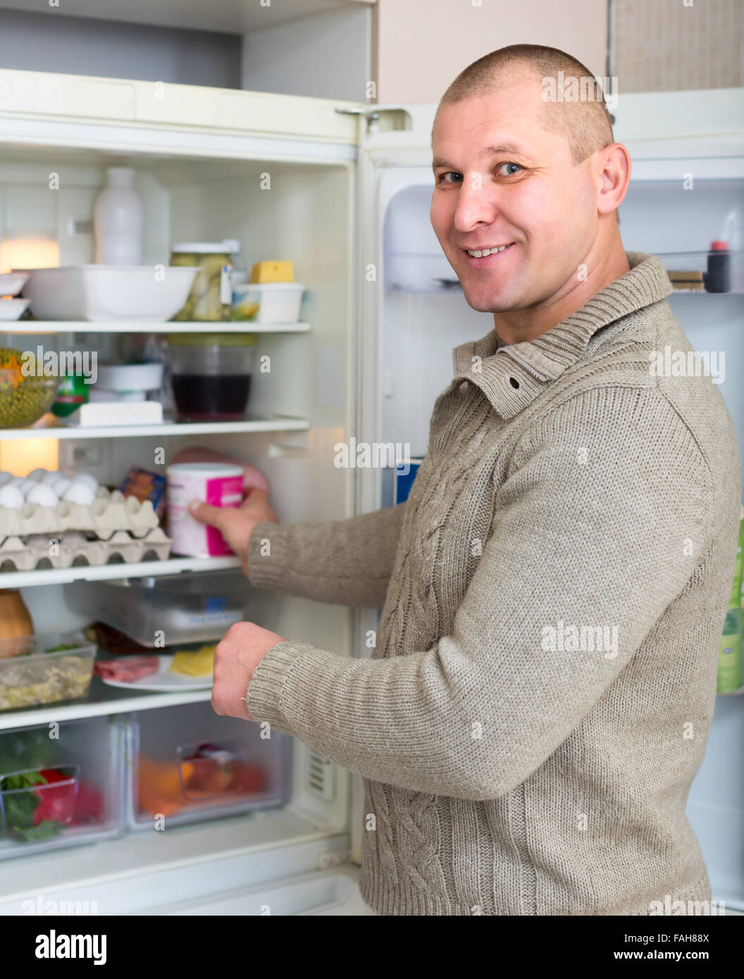Man indoors taking food from refrigerator Stock Photo - Alamy