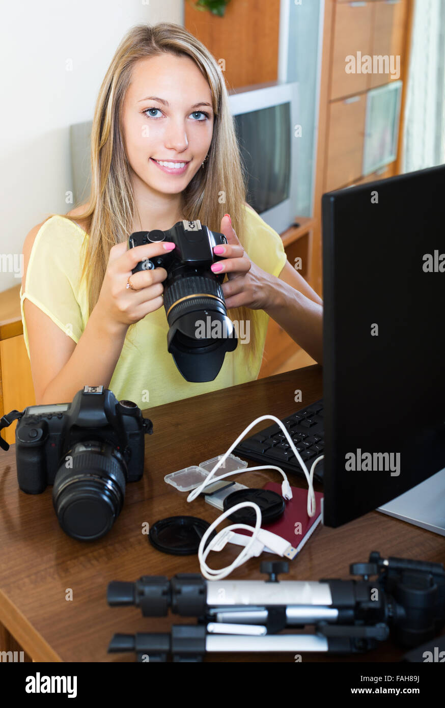 Smiling young woman working with photocamera and laptop at home Stock ...