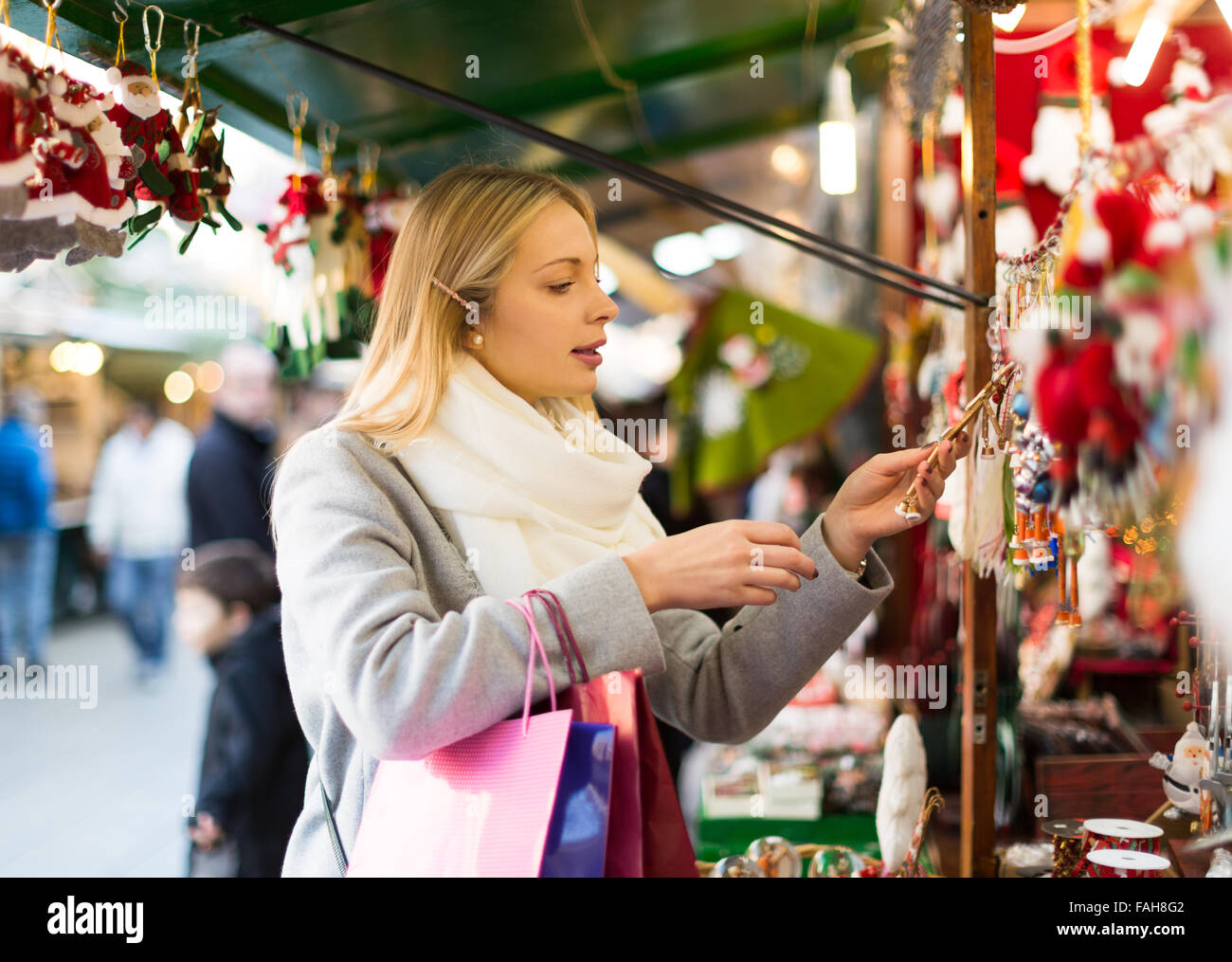 Portrait of blonde female customer near counter with Christmas gifts ...