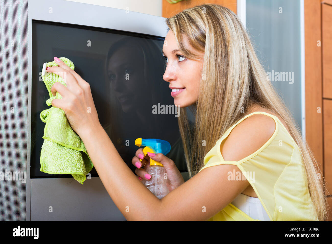 Blonde young girl cleaning TV with cleanser at home Stock Photo - Alamy